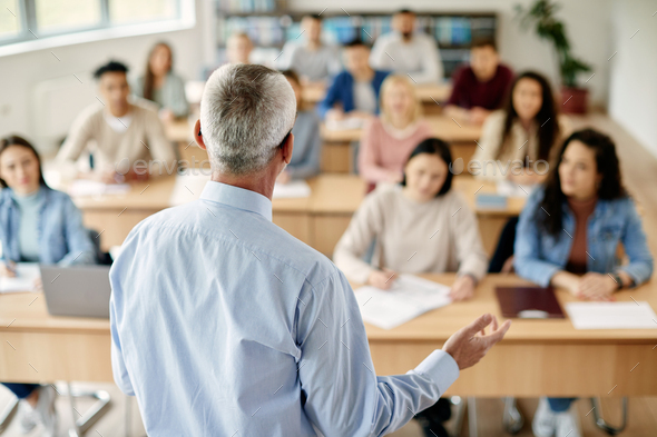 Rear view of professor giving lecture to large group of students at the university. Stock Photo ...